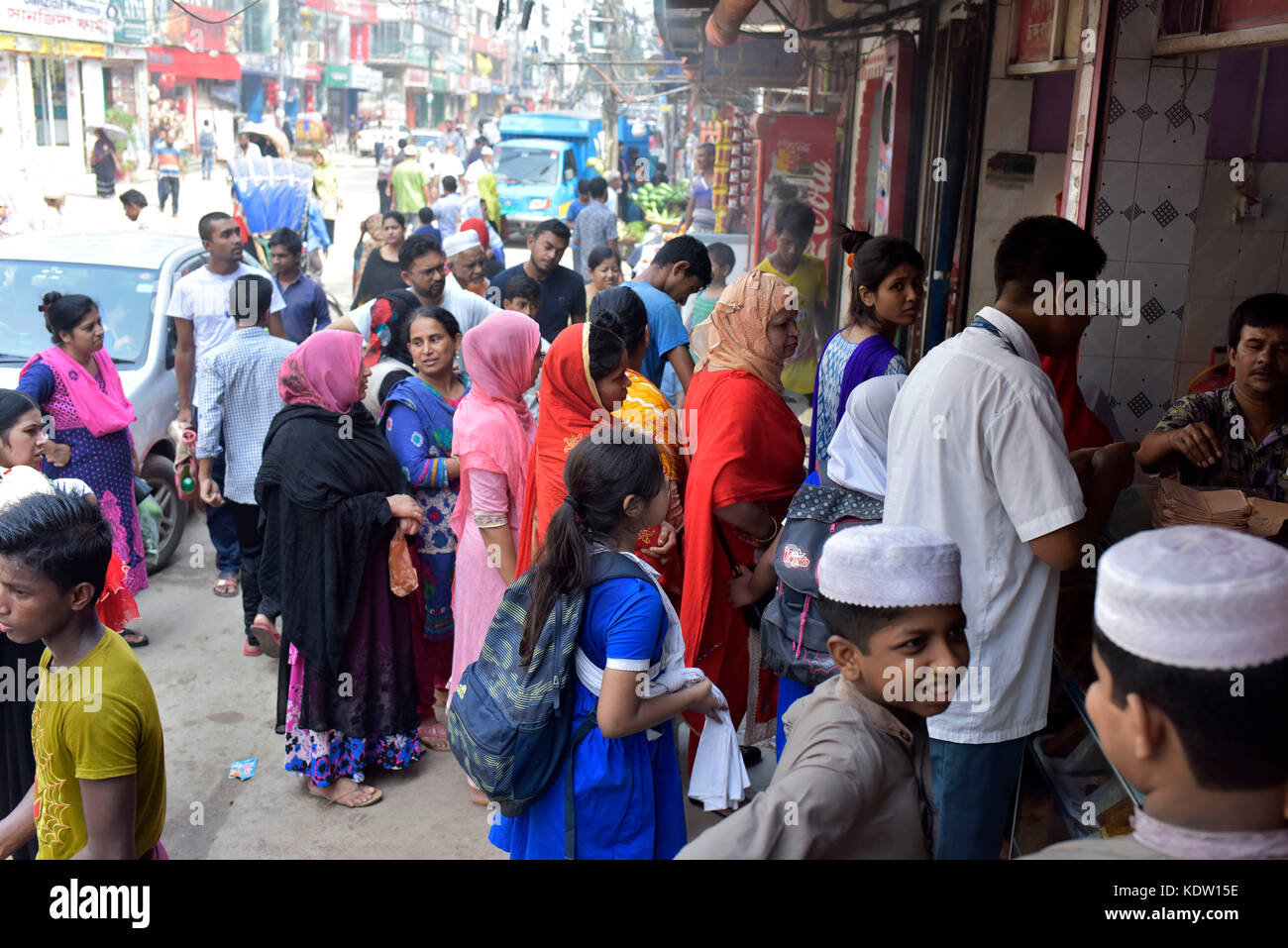DHAKA, BANGLADESH – OCTOBER 16, 2017: Bangladeshi people wait in a queue to buy foods from a ...
