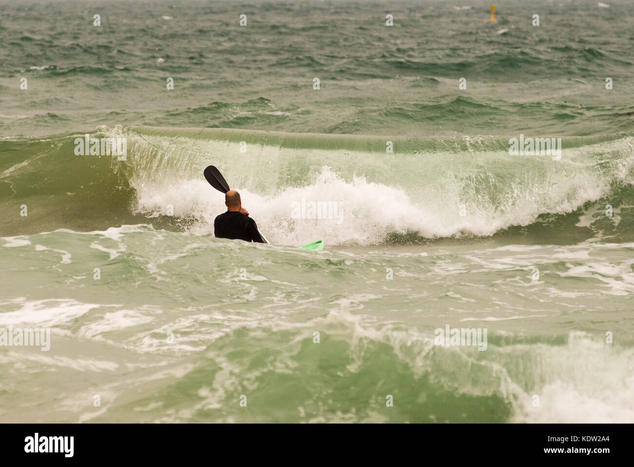 Surfer paddling through big waves and strong winds from storm, ex ...