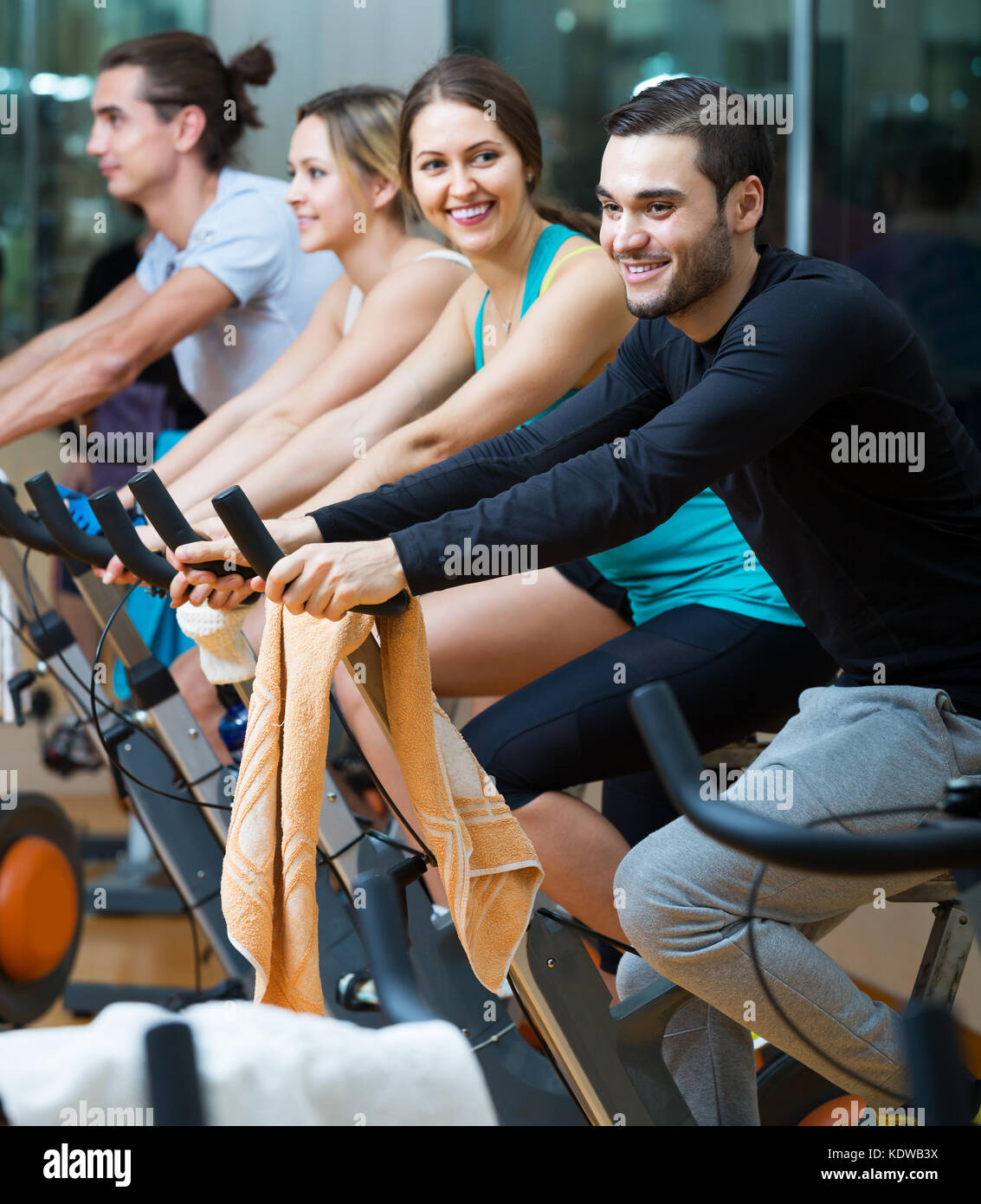 Group of positive adult people training on exercise bikes in gym Stock ...