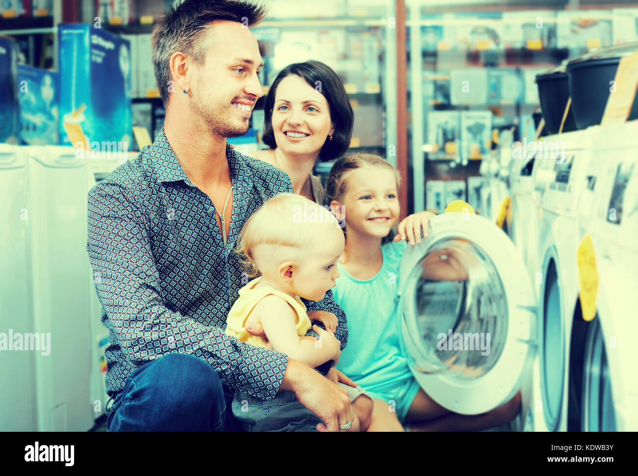 Smiling family with kids shopping washing machine in household store ...