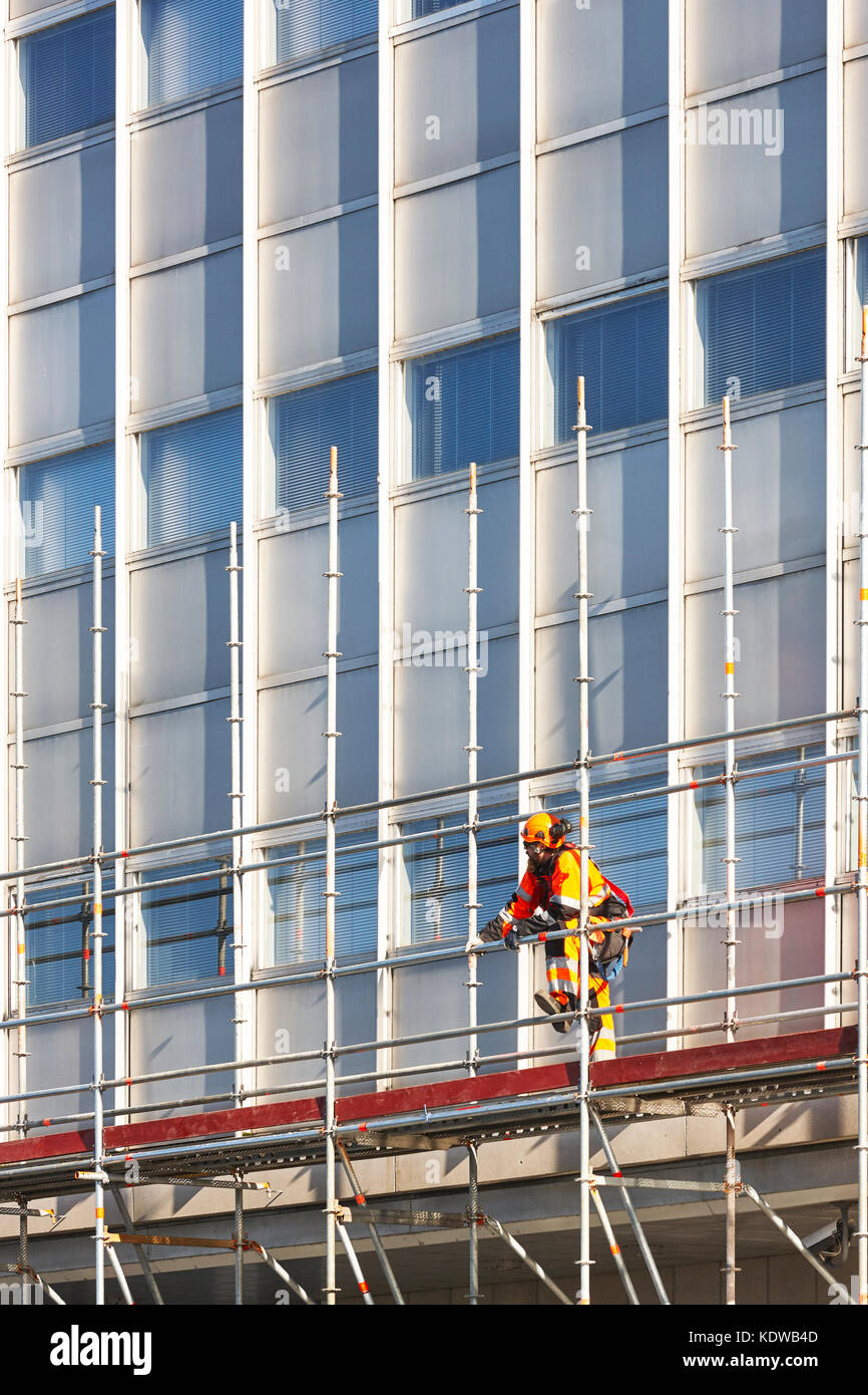 Construction worker mounting a scaffolding structure on a building ...