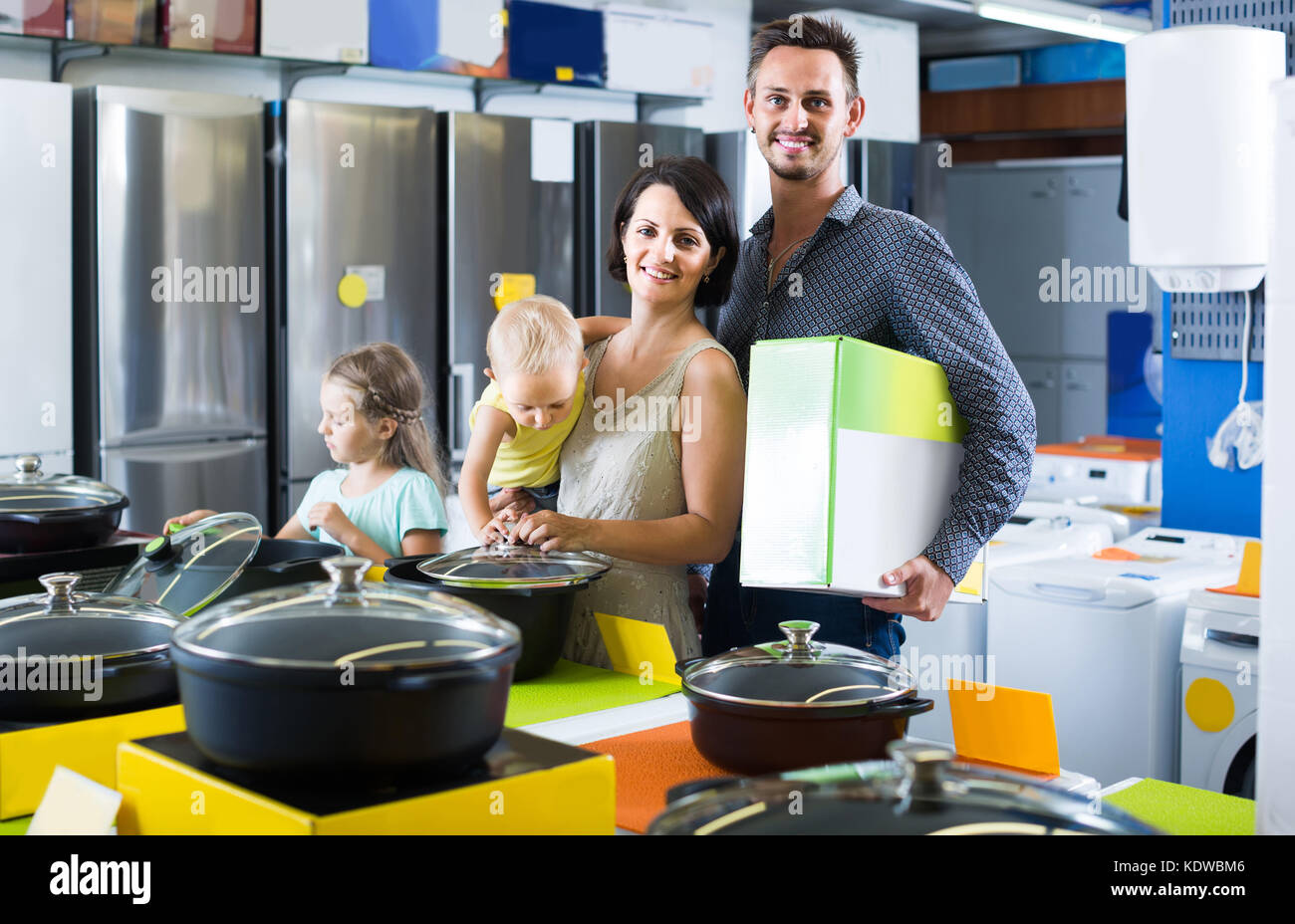smiling russian couple with two children picking new kitchenware in ...