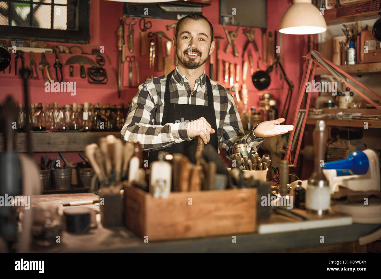 Young positive smiling efficient male worker demonstrating workplace ...