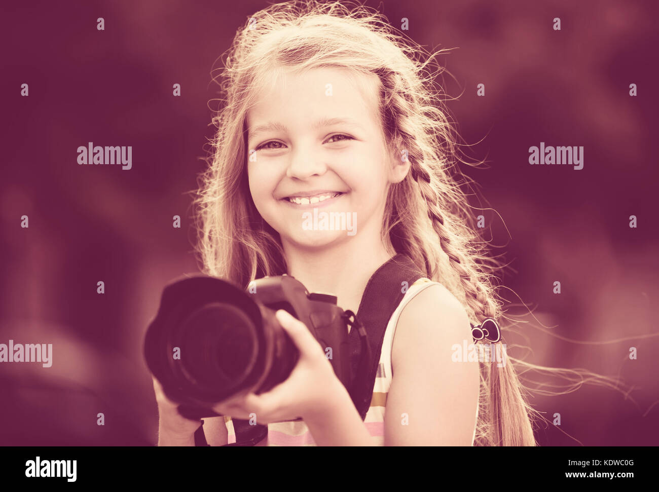 cheerful female child taking pictures with camera in park on summer day ...