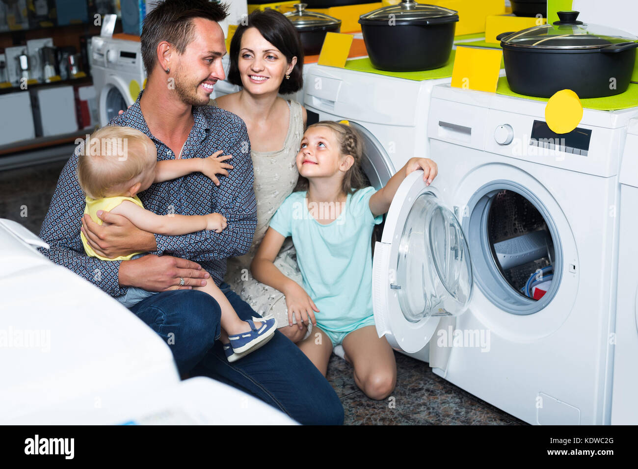 smiling russian parents with two kids choosing washing machine in home ...