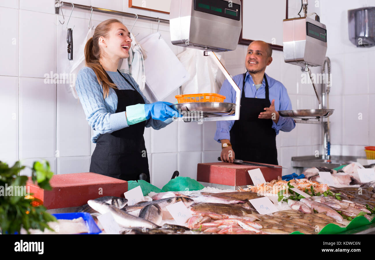 Two cheerful smiling sellers standing at the counter at ordinary fish ...