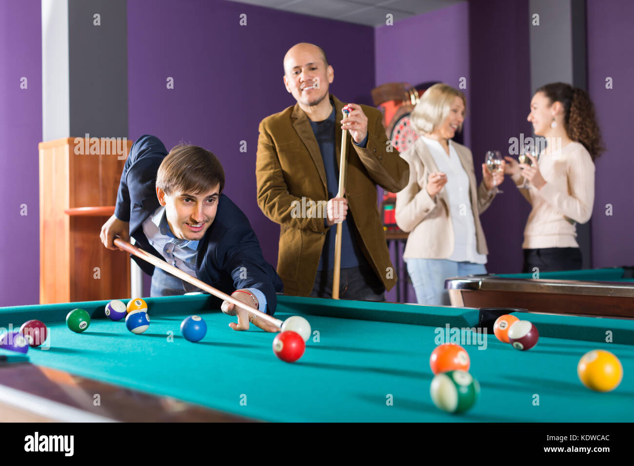 Cheerful smiling colleagues having pool game in billiard club after ...