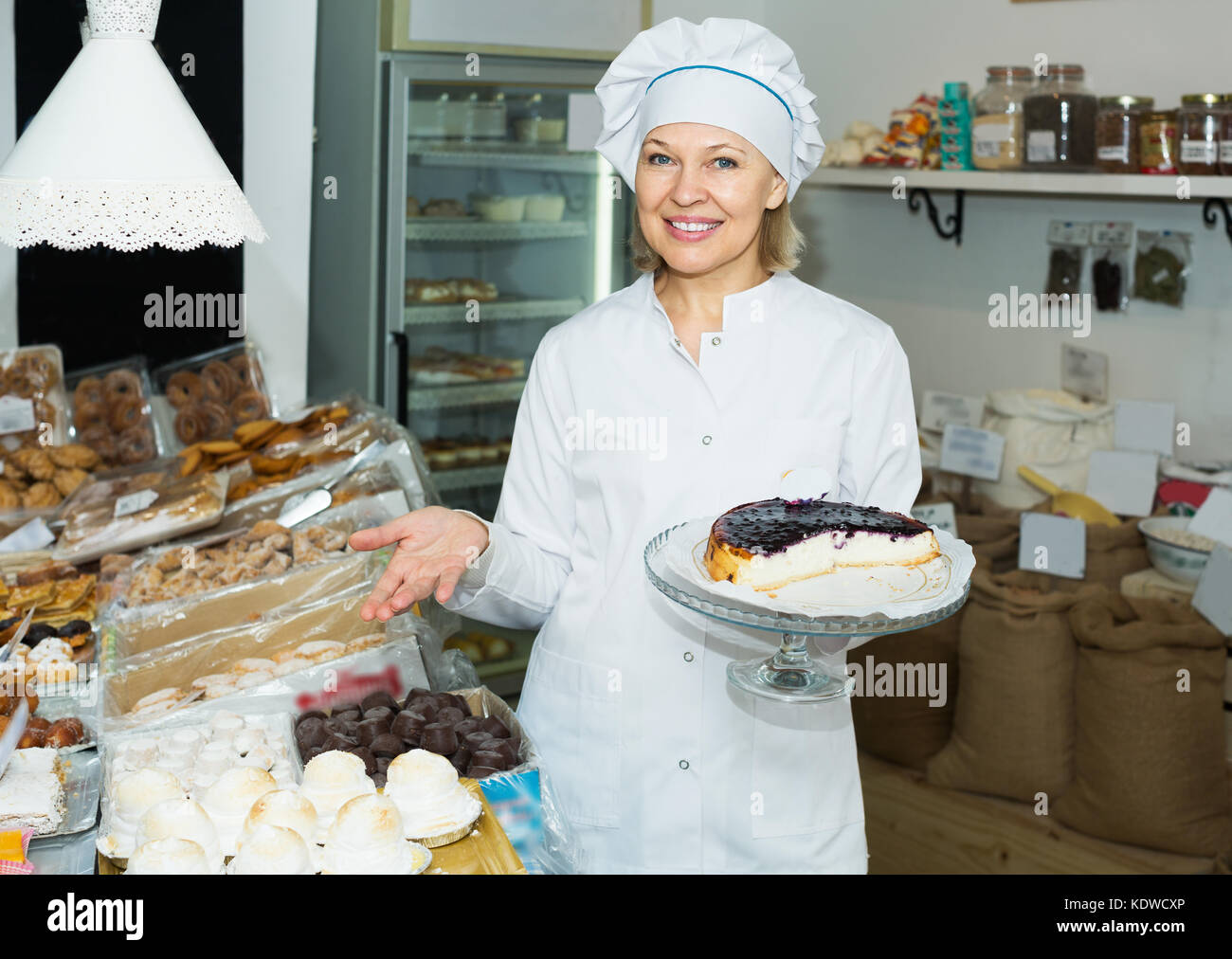 Happy woman offering fresh and tasty pastry in bakery Stock Photo - Alamy