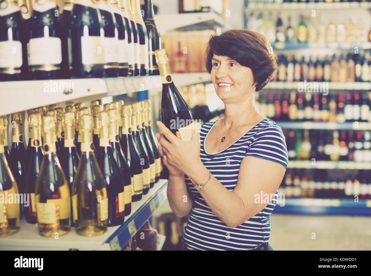 Cheerful pensioner selecting a wine at the grocery store Stock Photo ...