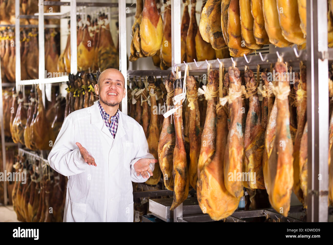 Mature butcher posing with jamon joints at the meat factory Stock Photo ...