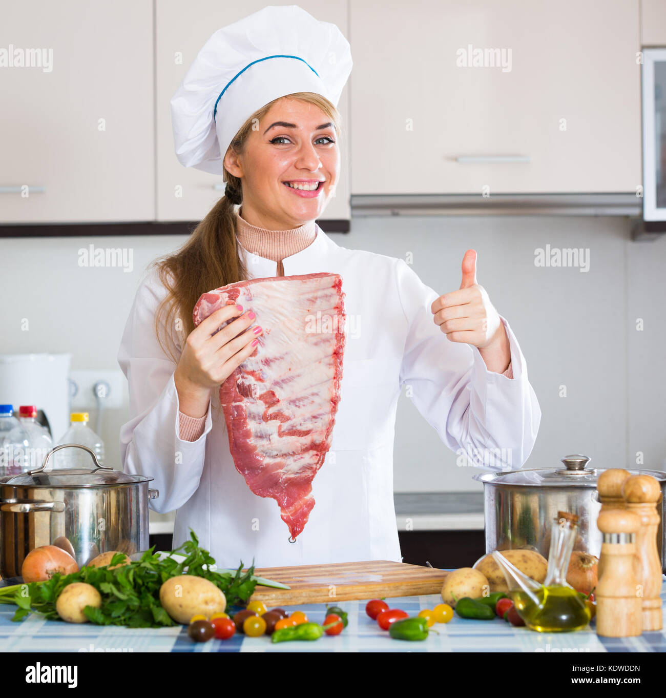 Happy female chef posing with pork ribs in domestic kitchen Stock Photo ...