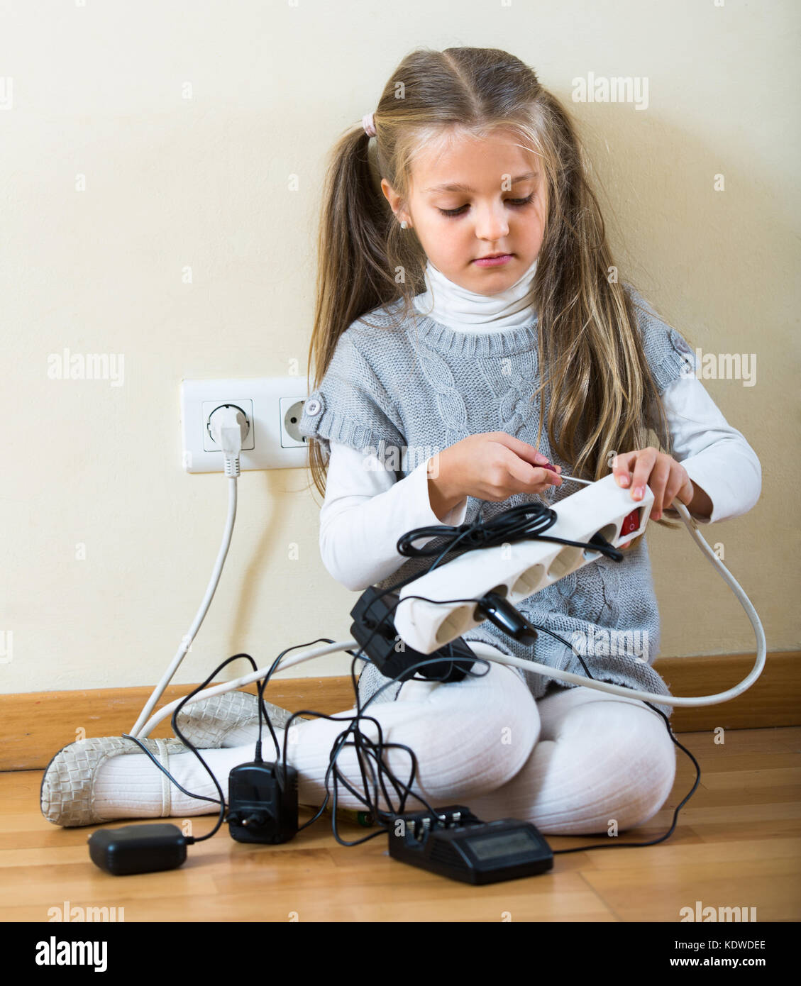 Risky little girl dangerously playing with sockets and electricity ...