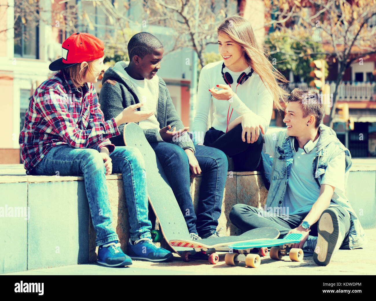 Group of positive smiling teenage friends relaxing and chatting in town ...