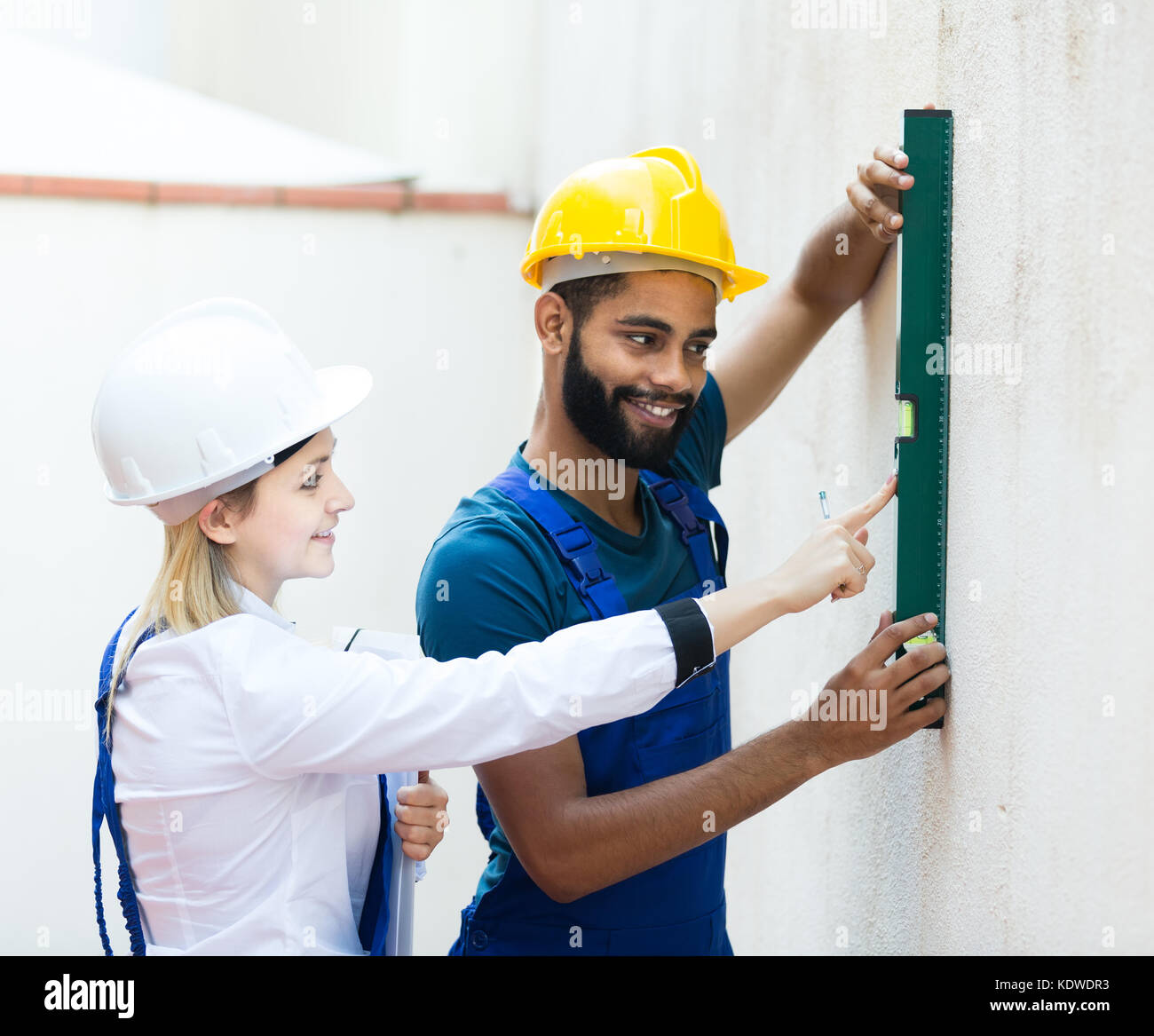 Constructor and smiling american professional builder with spirit level ...