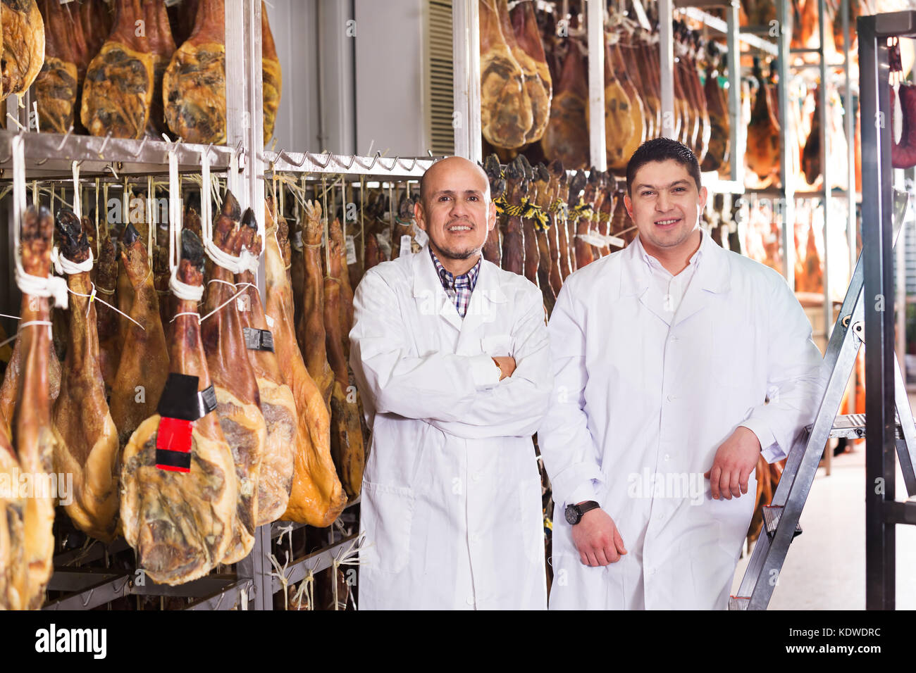 Mature butcher and his assistant with a jamon joints at the meat ...