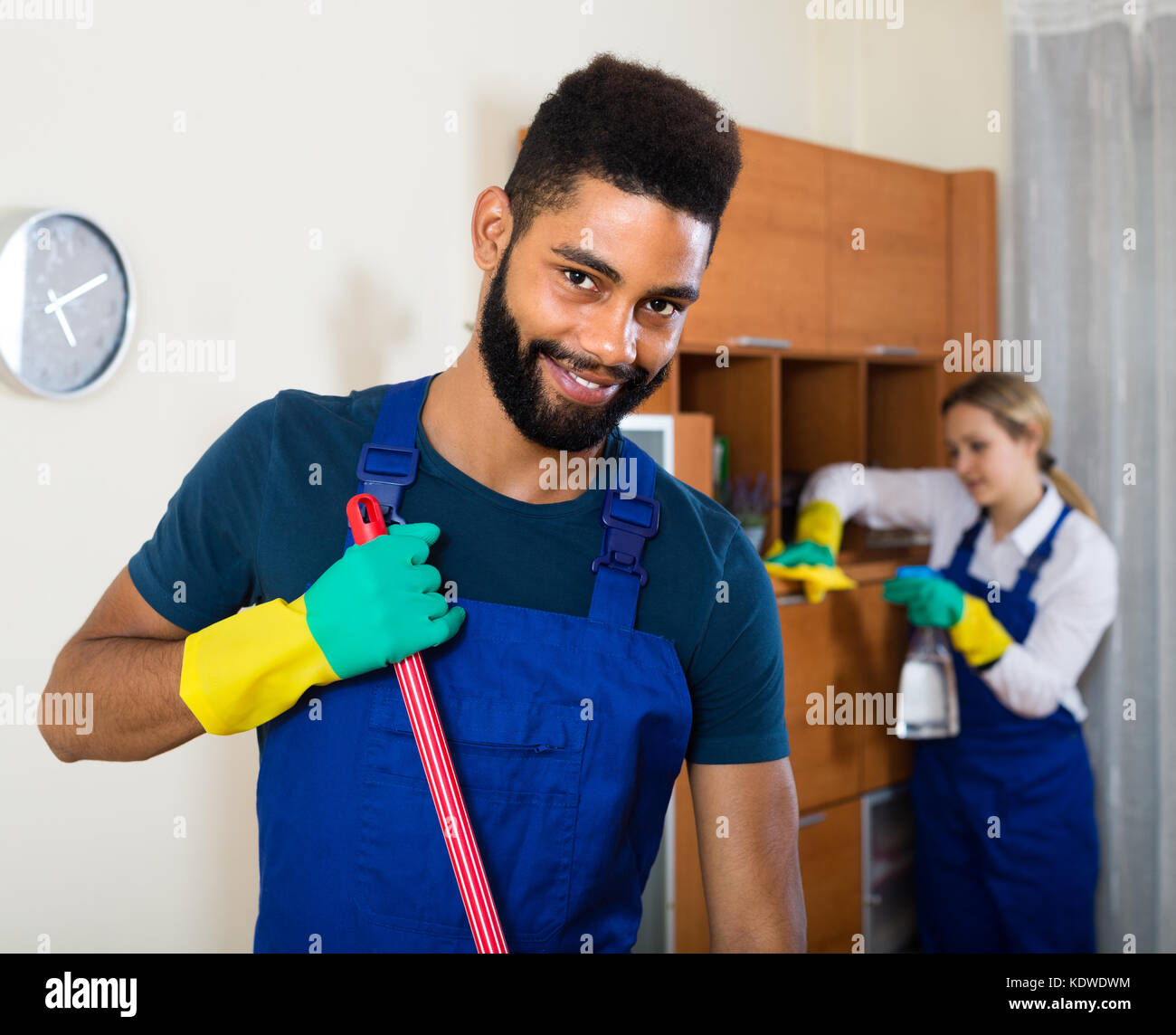 Team of black and white professional cleaners in overalls working ...