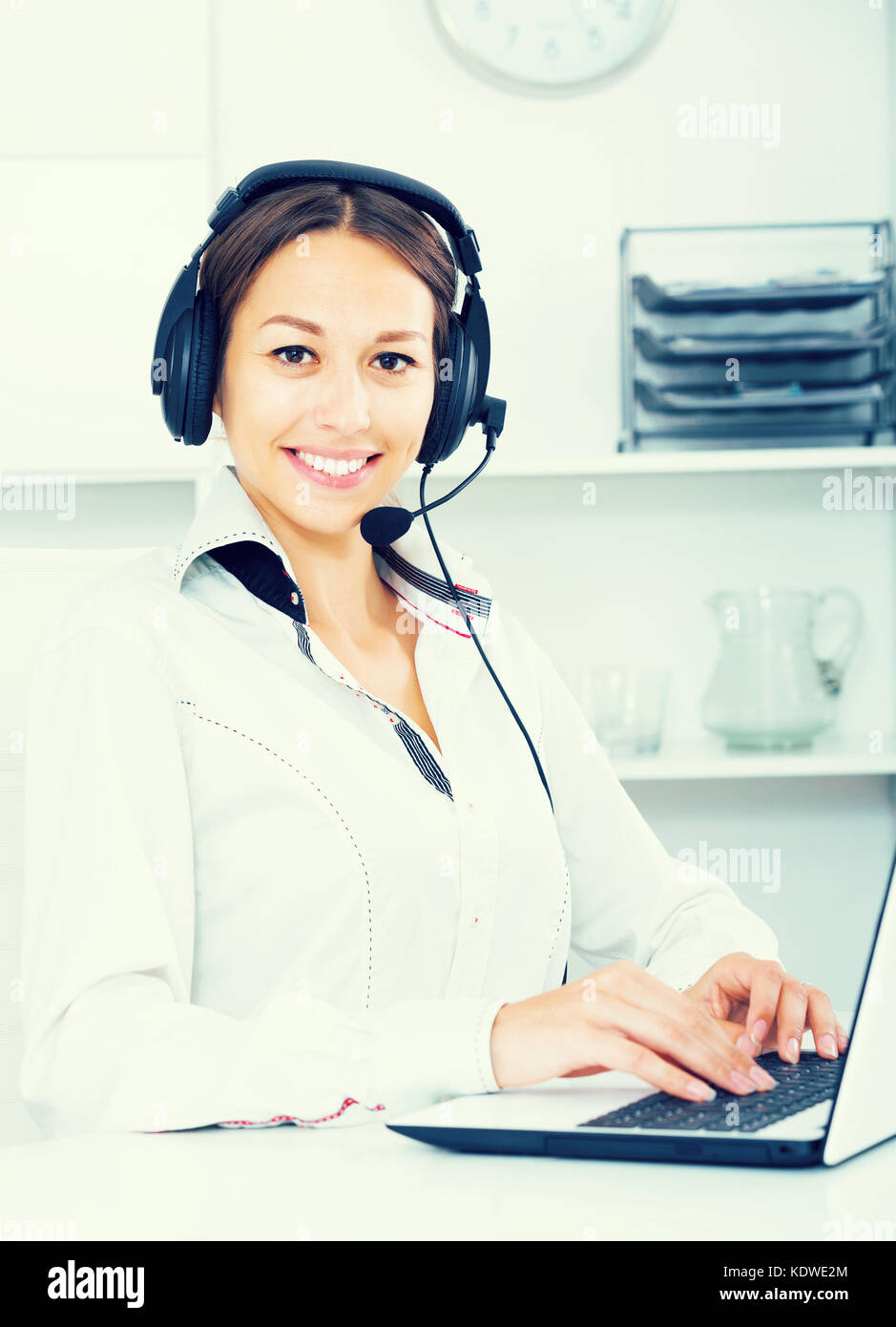 Happy adult brunette woman talking with customer using hands-free set ...