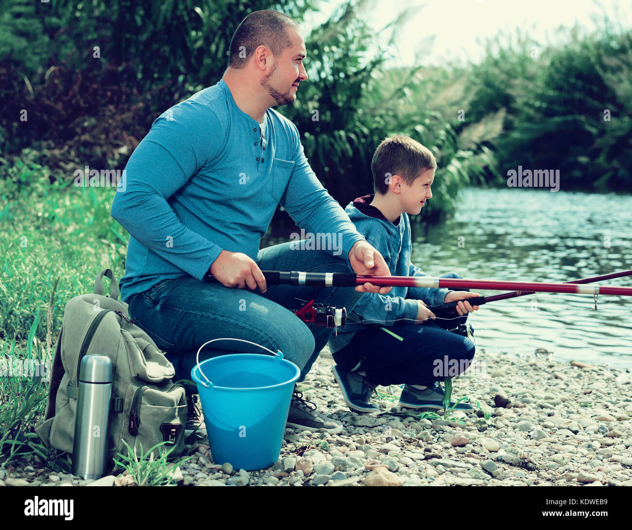 Cheerful father and boy fishing with rods in summer day Stock Photo - Alamy