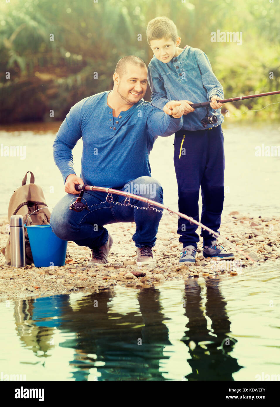 Portrait of glad smiling father and cute son fishing with rods in ...