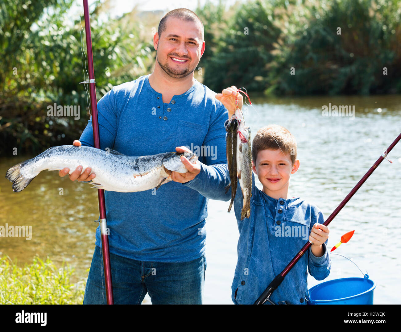 Portrait of happy friendly laughing father and cute son fishing with ...