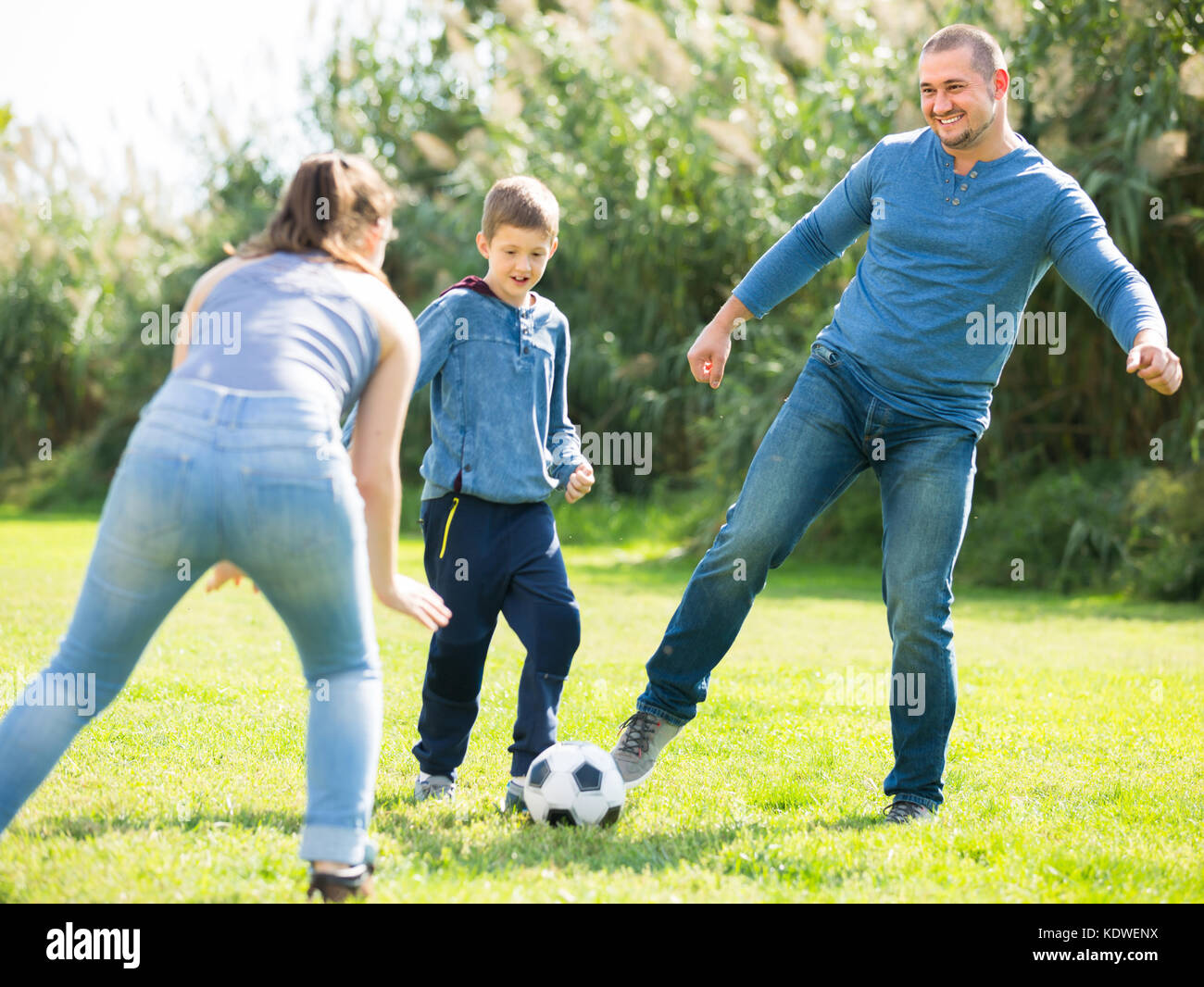 Happy son and parents playing football in grass field Stock Photo - Alamy