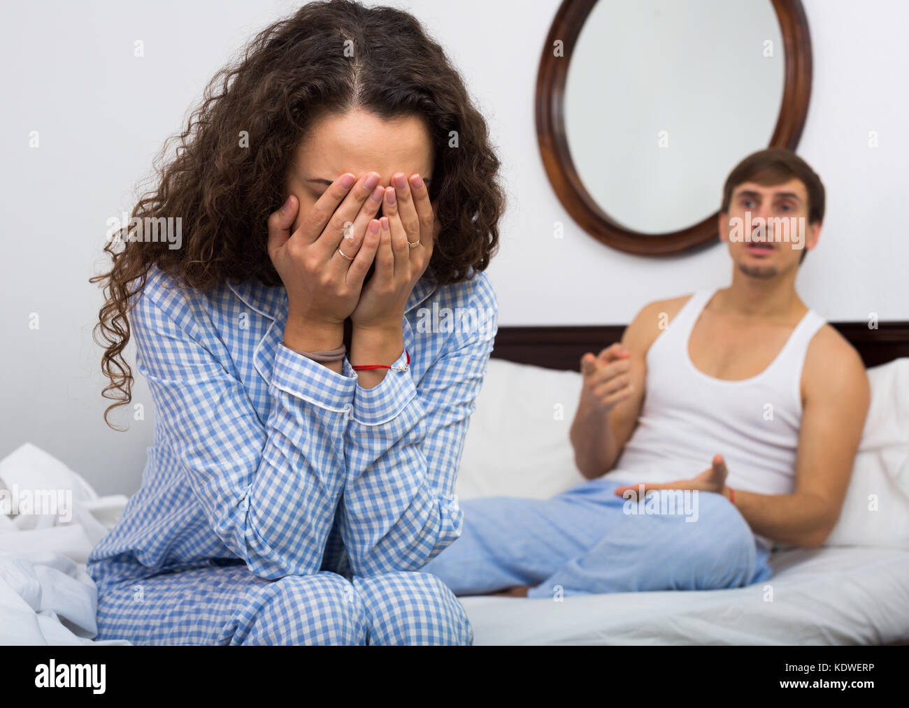 Angry young woman turned away from man in bed Stock Photo - Alamy