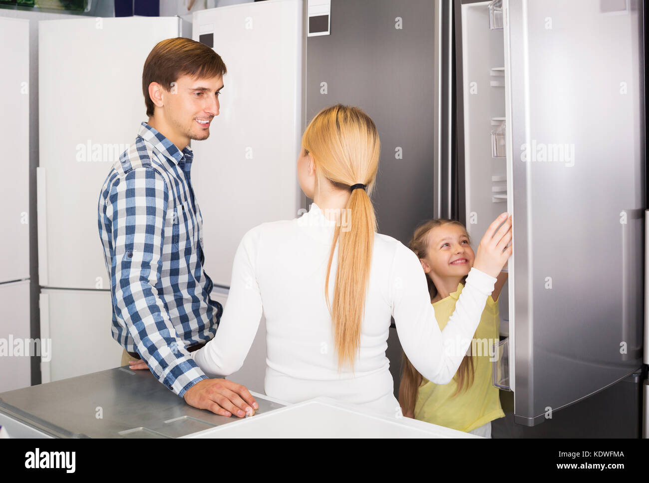 Smiling family selecting refrigerator in appliance store Stock Photo ...