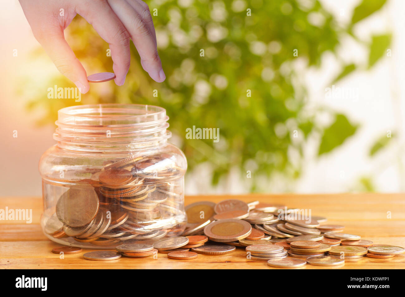 hand put money on plastic jar and pile of coins, concept in growth ...