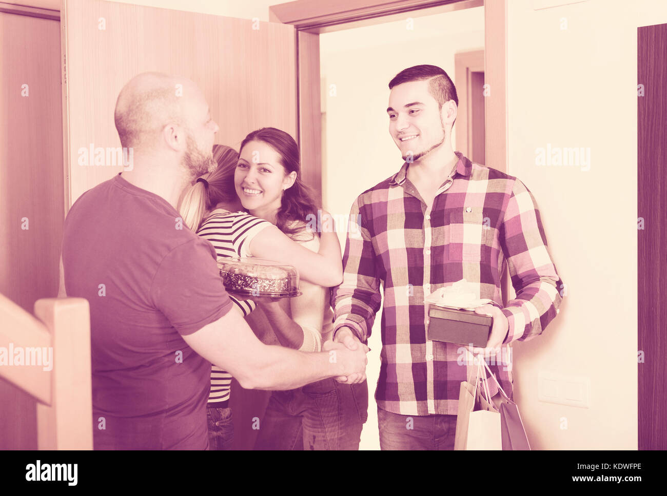 Positive guests with presents and cake standing in doorway. Focus on ...