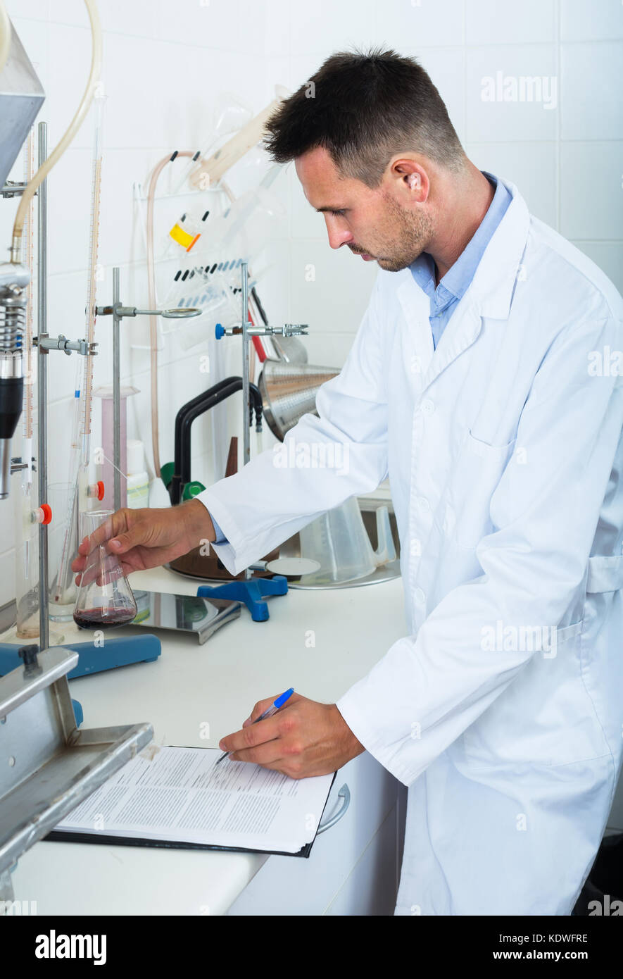 attentive adult american man making tests in wine manufactory ...
