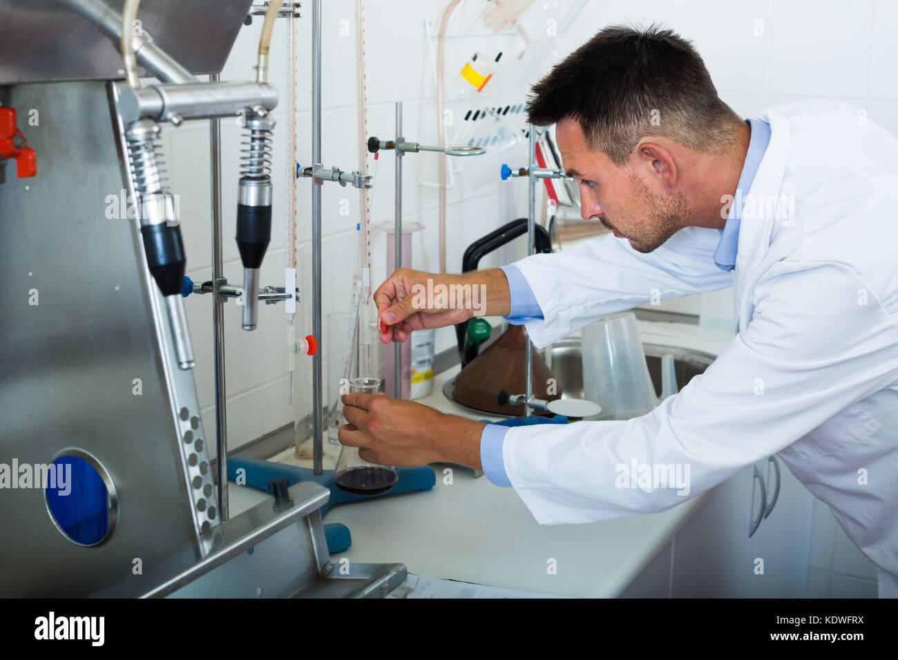 Man in white coat working on quality of products in winery lab Stock ...