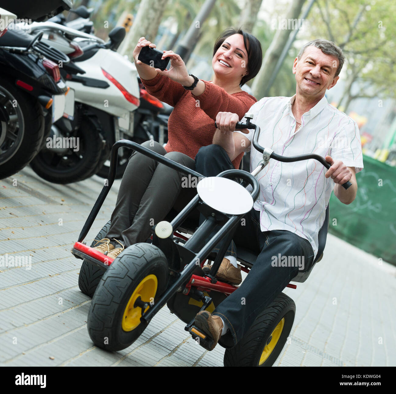 Mature couple 45-55 years old driving double bike outside and making ...