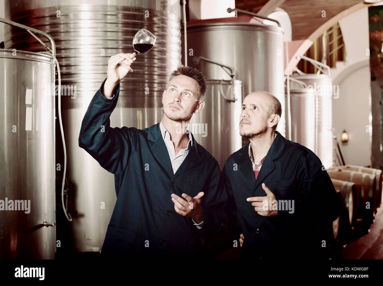 Two attentive men coworkers wearing uniform standing with glass of wine ...