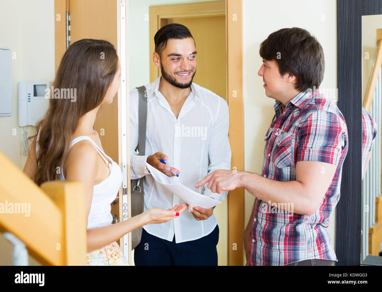 Smiling adult salesman came home to the merried couple and stands in ...