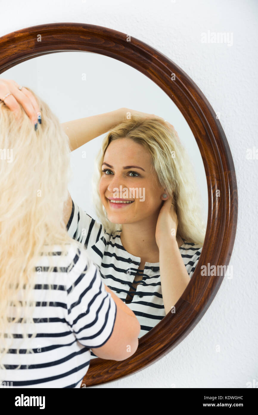 Young woman looking in mirror after waking up Stock Photo - Alamy