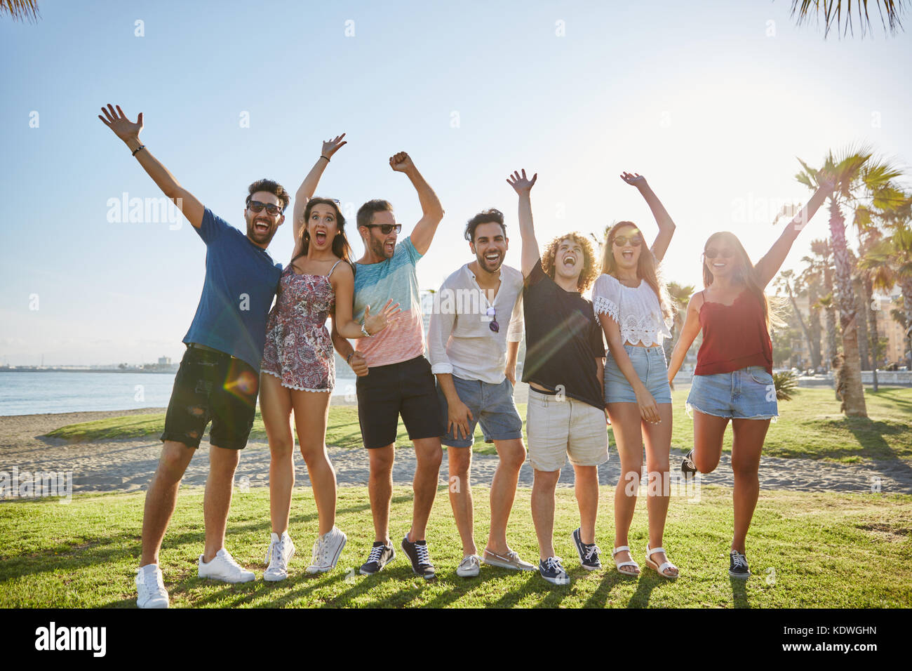 Portrait of group of friends raising hands together outside laughing ...