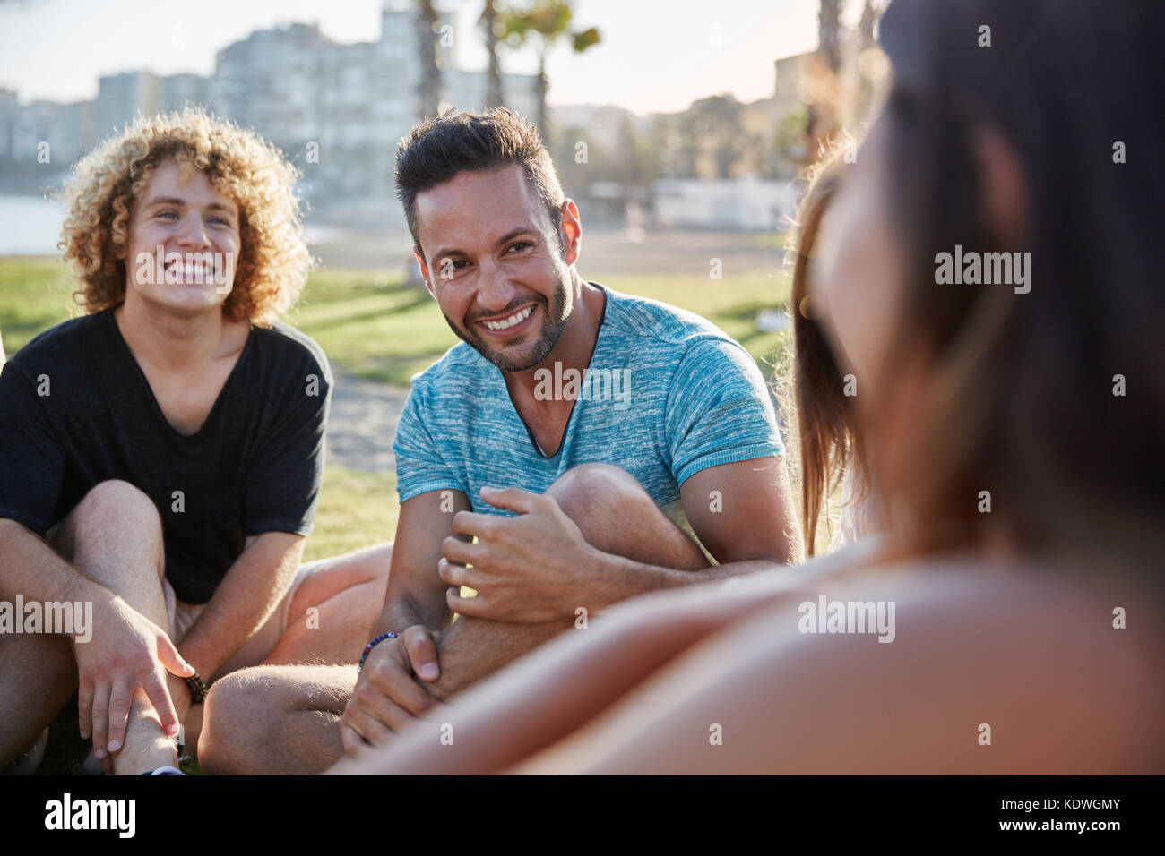 Portrait of two happy men sitting with friends outside laughing Stock ...