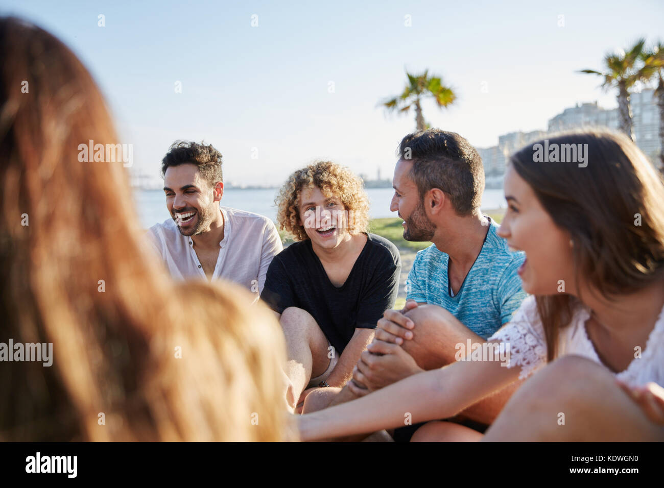 Portrait of happy friends sitting outside together laughing Stock Photo ...