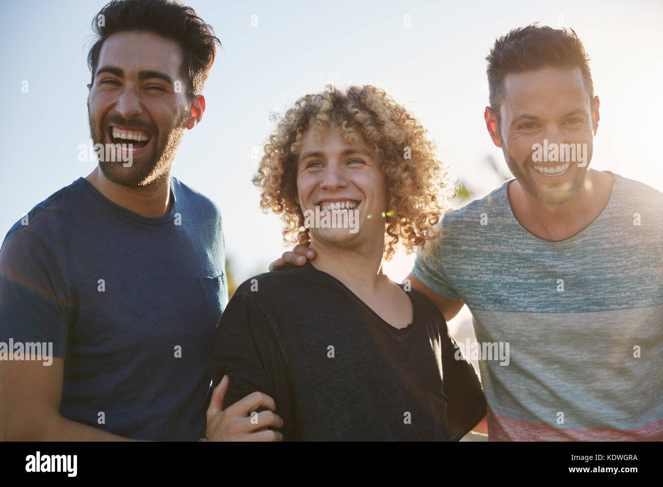 Portrait of three handsome male friends laughing together outside Stock ...