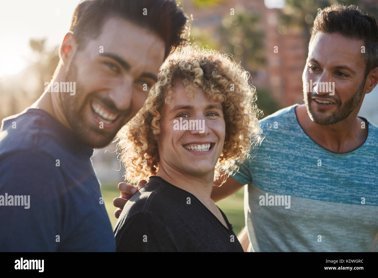 Portrait of handsome man standing with friends outside laughing Stock ...