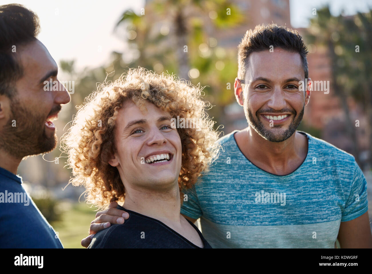Portrait of handsome man standing outside with friends smiling Stock ...