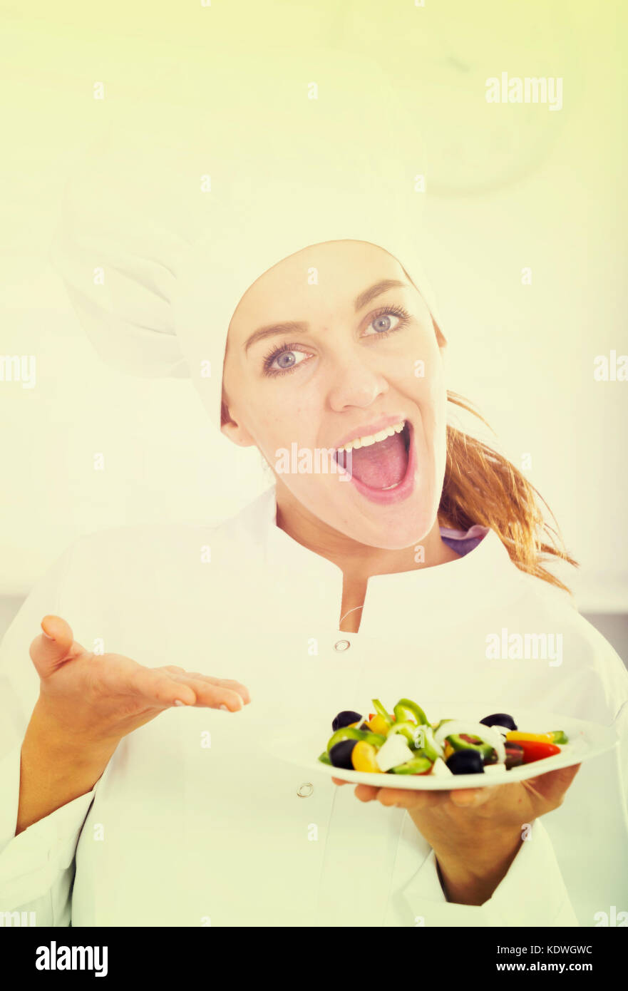 portrait of happy young coosie woman with chestnut hair showing salad ...