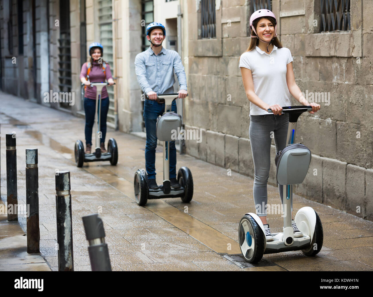 Group of smiling three friends posing on segways on city street Stock ...