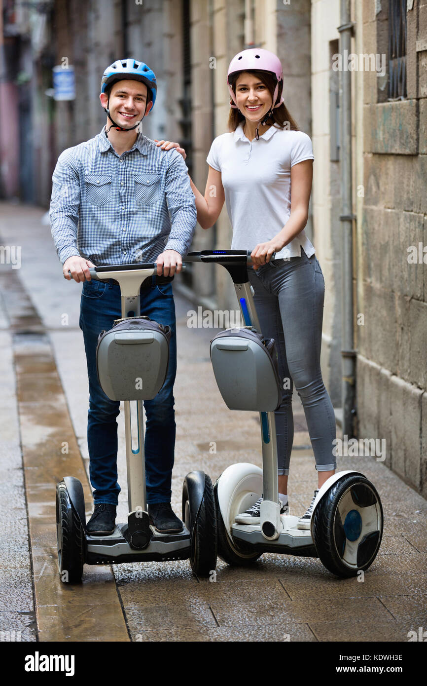 Positive cheerful laughing boy and girl posing on segways in vacation ...