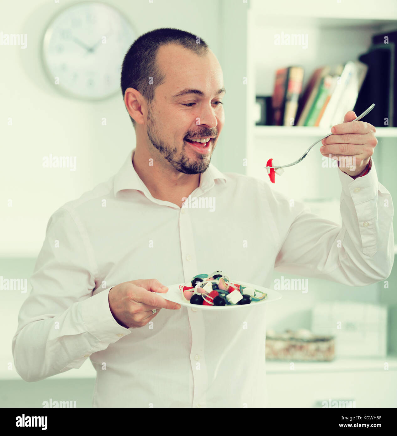 Positive young man ready to eat greek salad in office Stock Photo - Alamy