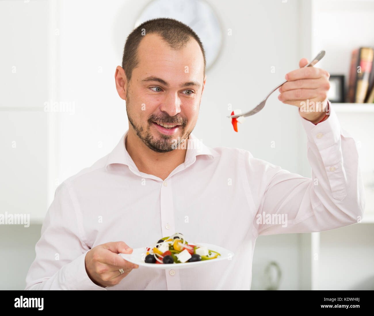 Positive young man ready to eat greek salad in office Stock Photo - Alamy