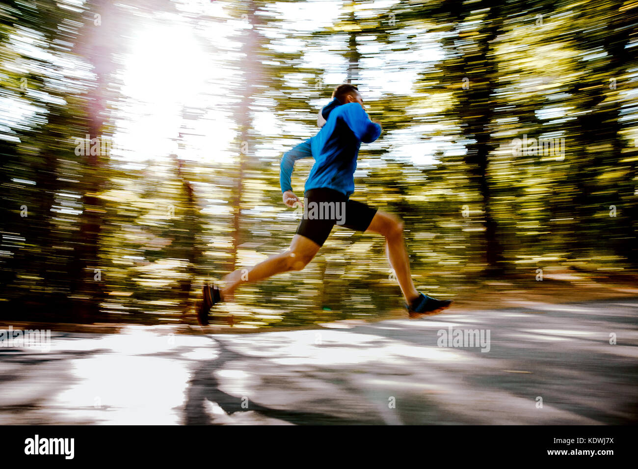 blurred motion male athlete runner running on a forest road Stock Photo ...