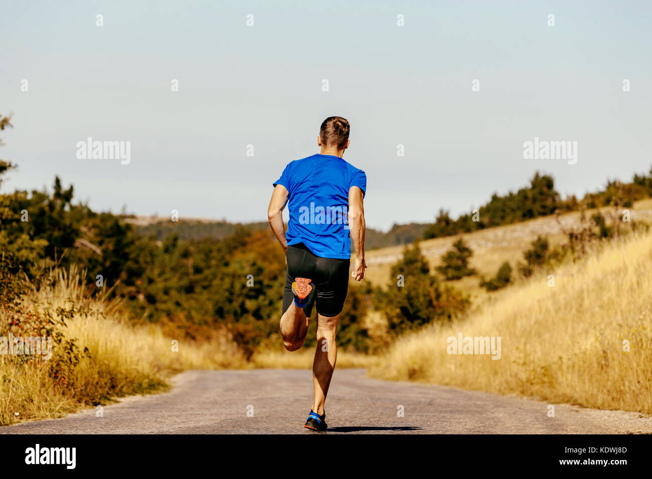 back male runner dynamic running on road autumn yellow grass of field ...