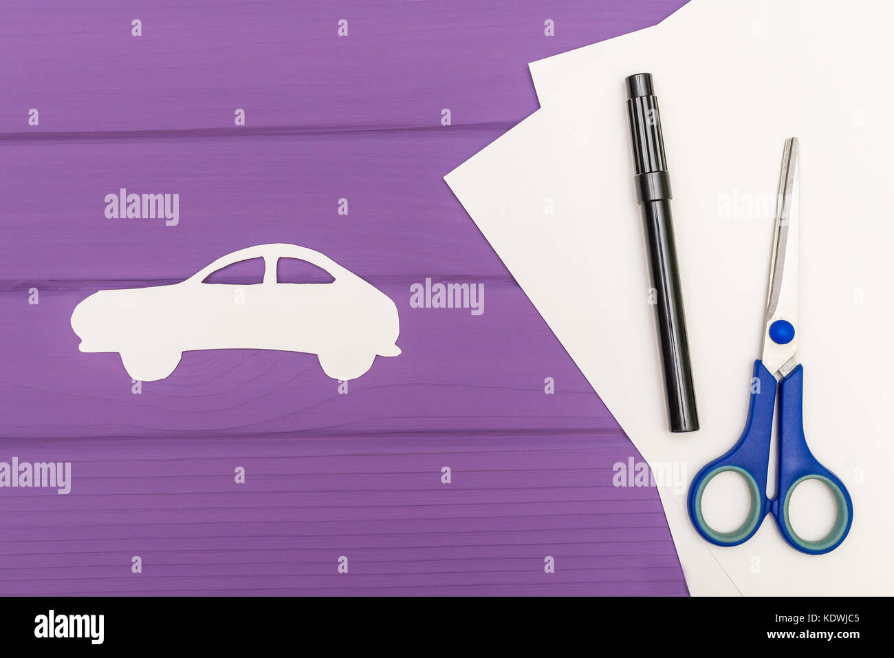 The silhouettes cut out of paper of car, scissors and marker near on a ...