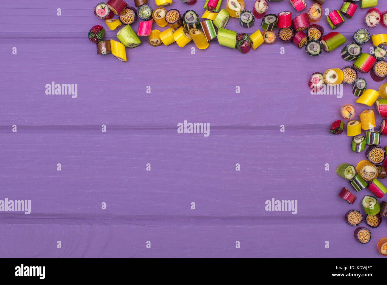 A corner frame made of colored caramel candies on wooden purple ...